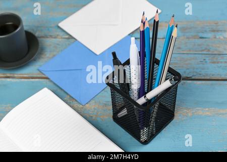 Holder with stationery, notebooks and vase with flowers on wooden ...