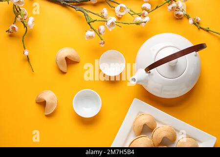 Fortune cookies, teapot, cups and sakura on yellow background. Chinese ...