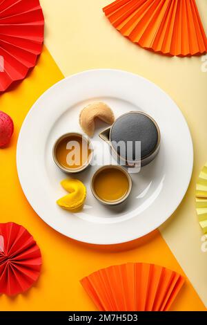 Plate with fortune cookies, teapot, cups and Chinese symbols on color ...