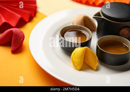 Plate with fortune cookies, teapot, cups and Chinese symbols on color ...