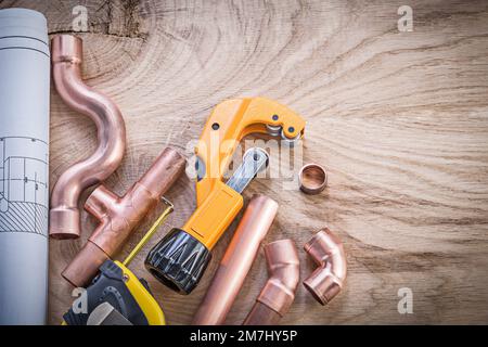 Construction plans tape line water pipe cutter fixtures on wooden board ...