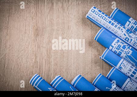 Pile of blue rolled engineering drawings on wooden board construction ...