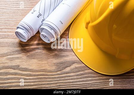 Rolled engineering drawings hard hat on fluted metal background ...