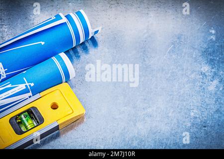 Rolled up engineering drawings construction level on scratched metallic ...