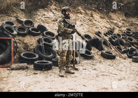 Mature soldier standing near the shooting target with rifle in hands ...