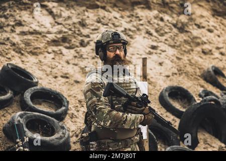 Mature soldier standing near the shooting target with rifle in hands ...