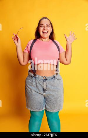 Overweight happy woman over bright yellow background around many ...