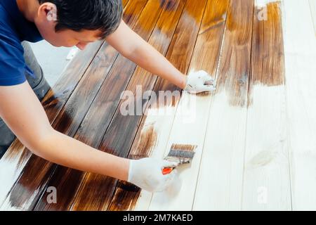 Man paints wooden boards with paint brush. Carpenter cabinetmaker ...