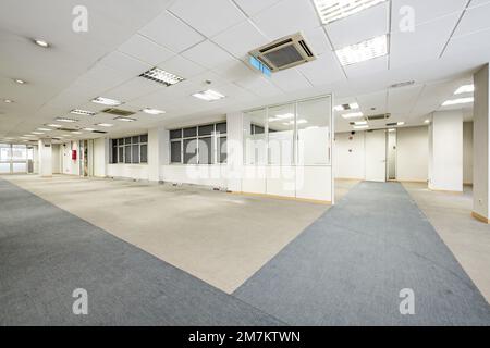 An empty office with two-tone carpeted floors, a space with partitions ...