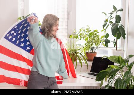 Happy woman employee sitting wrapped in USA flag, shouting for joy in ...