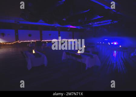 A dark empty venue with decorated tables and lights Stock Photo - Alamy