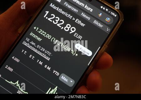 A man holding a mobile phone with an Ethereum Binance counter on screen ...