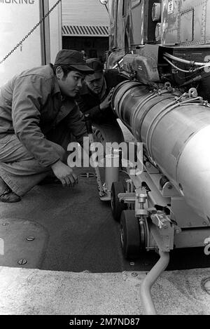 Two crewmen, aboard the frigate USS TRIPPE (FF-1075), load a Mark 46 ...