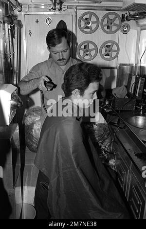 A crewman aboard the attack submarine USS BONEFISH (SS-582) reads ...