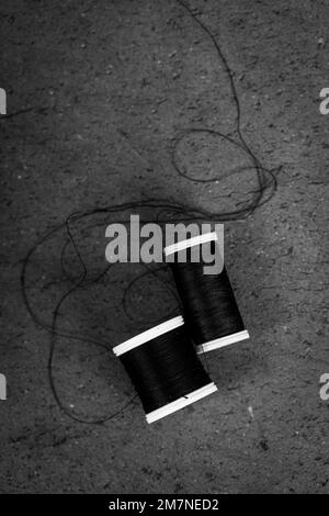 Black grey gray thread spools with needle background with copy space ...