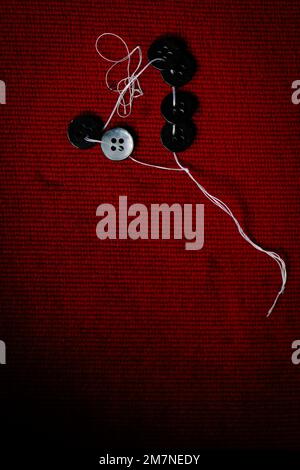 White buttons with a red thread Stock Photo - Alamy