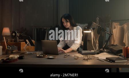 Female tailor works on new clothes collection in luxury atelier. She ...