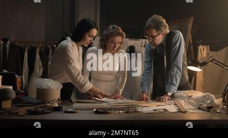 Cinematic shot of tailors and woman discussing sketches of wedding ...