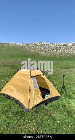 Vertical shot of a tent on a hill covered in greenery during a ...