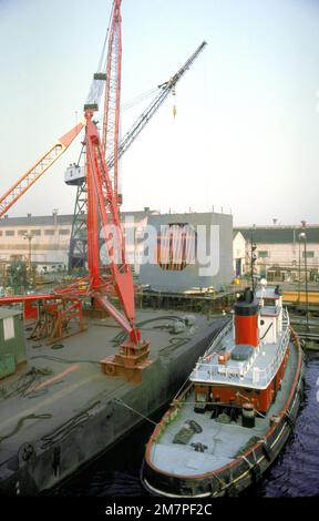 A lift barge/crane, being propelled by a tugboat on each side, carries ...