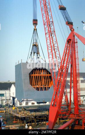 A lift barge/crane, being propelled by a tugboat on each side, carries ...