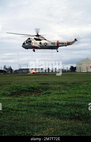 A ground-to-air view of an SH-3 Sea King helicopter airlifting a ...