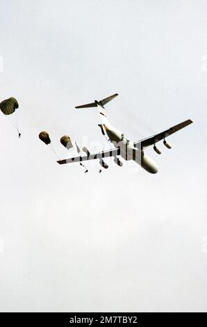 Parachutes open as a C-141 Starlifter aircraft drops personnel during ...