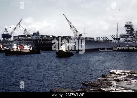 Tugs and barges pull the battleship NEW JERSEY (BB-62) out of drydock ...