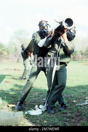 Crew members wearing gas masks, replace a rotor blade on an HH-3E Jolly ...