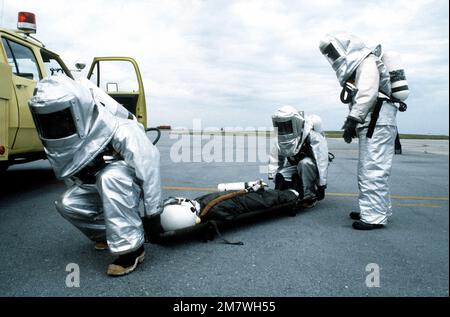 An "injured" space shuttle commander is carried on a stretcher by a ...