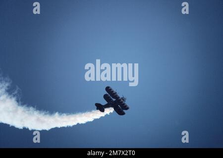 An antique bi-plane performs aerial stunts for guests attending the air ...