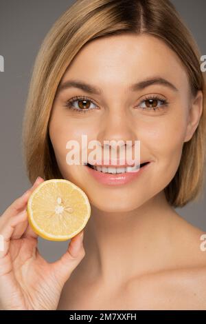 young woman with perfect skin holding cosmetic cream isolated on beige ...