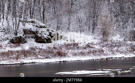 Scenic view of quiet transparent river with spots of white snow on the ...