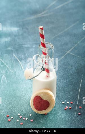 Heart shaped plate with cookie, bottle of wine and cutlery on color ...