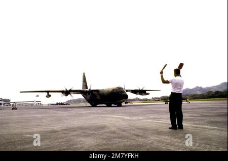 A plane director guides a C-130 Hercules aircraft to parking spaces on ...