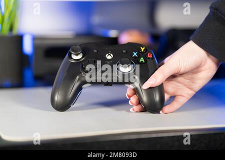 A girl's hand holding a black nacon xbox controller with painted finger ...