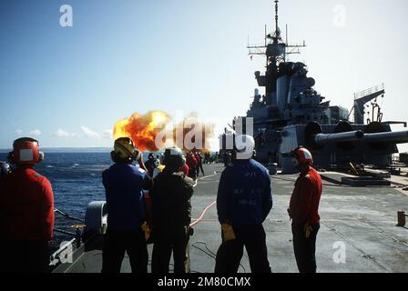 A 5-inch/38-caliber gun is fired off the port side of the battleship ...