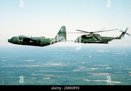 An air-to-air left side view of an HC-130 Hercules aircraft refueling a ...