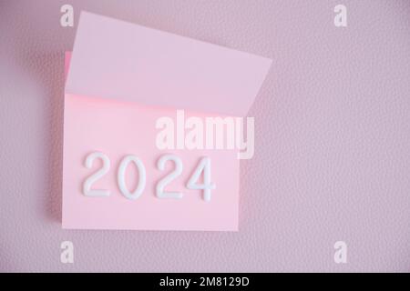Year 2024 is laid out in white numbers pink sheet.Concept time and new ...