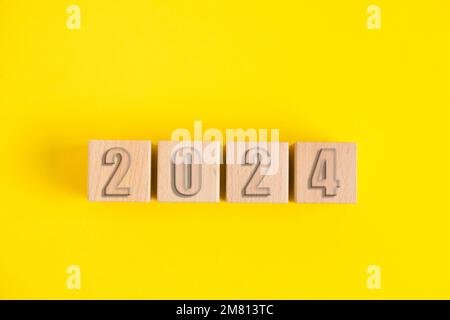 Wooden cubes with numbers 2024 yellow background are made by hand Stock ...