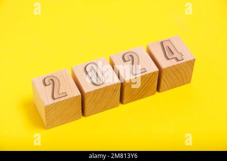 Wooden cubes with numbers 2024 yellow background are made by hand Stock ...