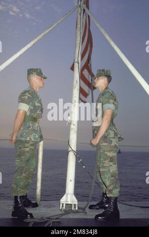 Marines lower the national ensign during evening colors aboard the ...