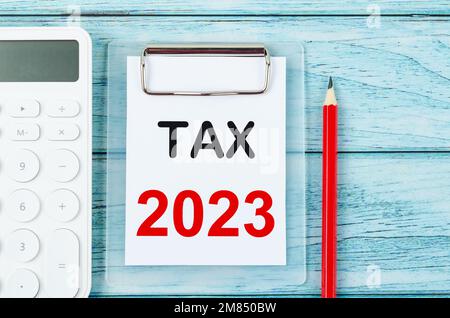 Tax 2023 text on clipboard with pen and calculator on wooden background ...