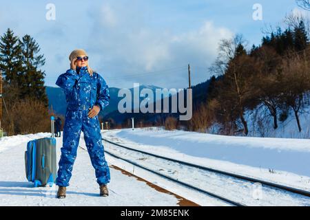 Woman pulling heavy luggage at a snow train station. Travelling by ...