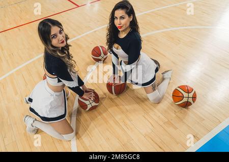 Cheerleaders in mini-skirts and knee-high socks holding pom-poms focus ...