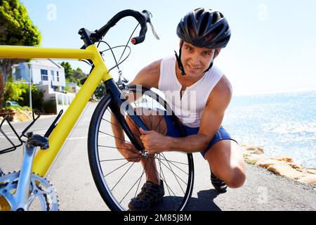 Changing his bike tyre. A young cyclist changing his bike tyre on the ...