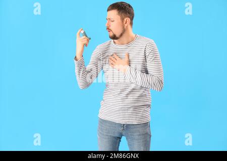 Sick man with inhaler on blue background Stock Photo - Alamy