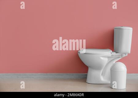 Ceramic toilet bowl near pink wall Stock Photo - Alamy