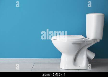 Ceramic toilet bowl near blue wall Stock Photo - Alamy