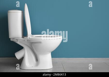 Ceramic toilet bowl near blue wall Stock Photo - Alamy